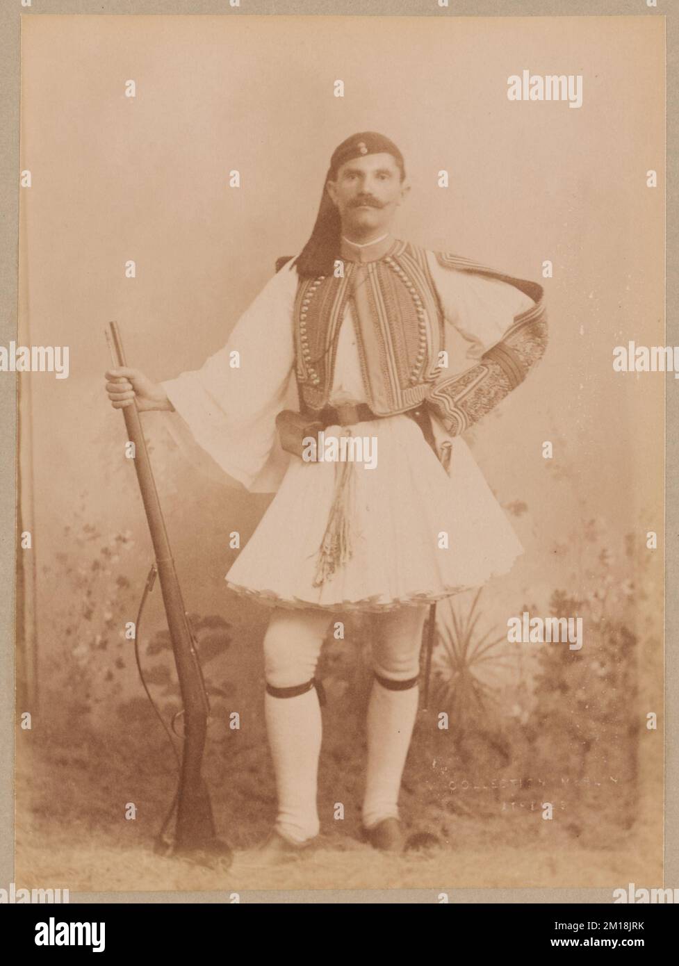 Studio portrait of man in traditional Greek dress holding a rifle ...