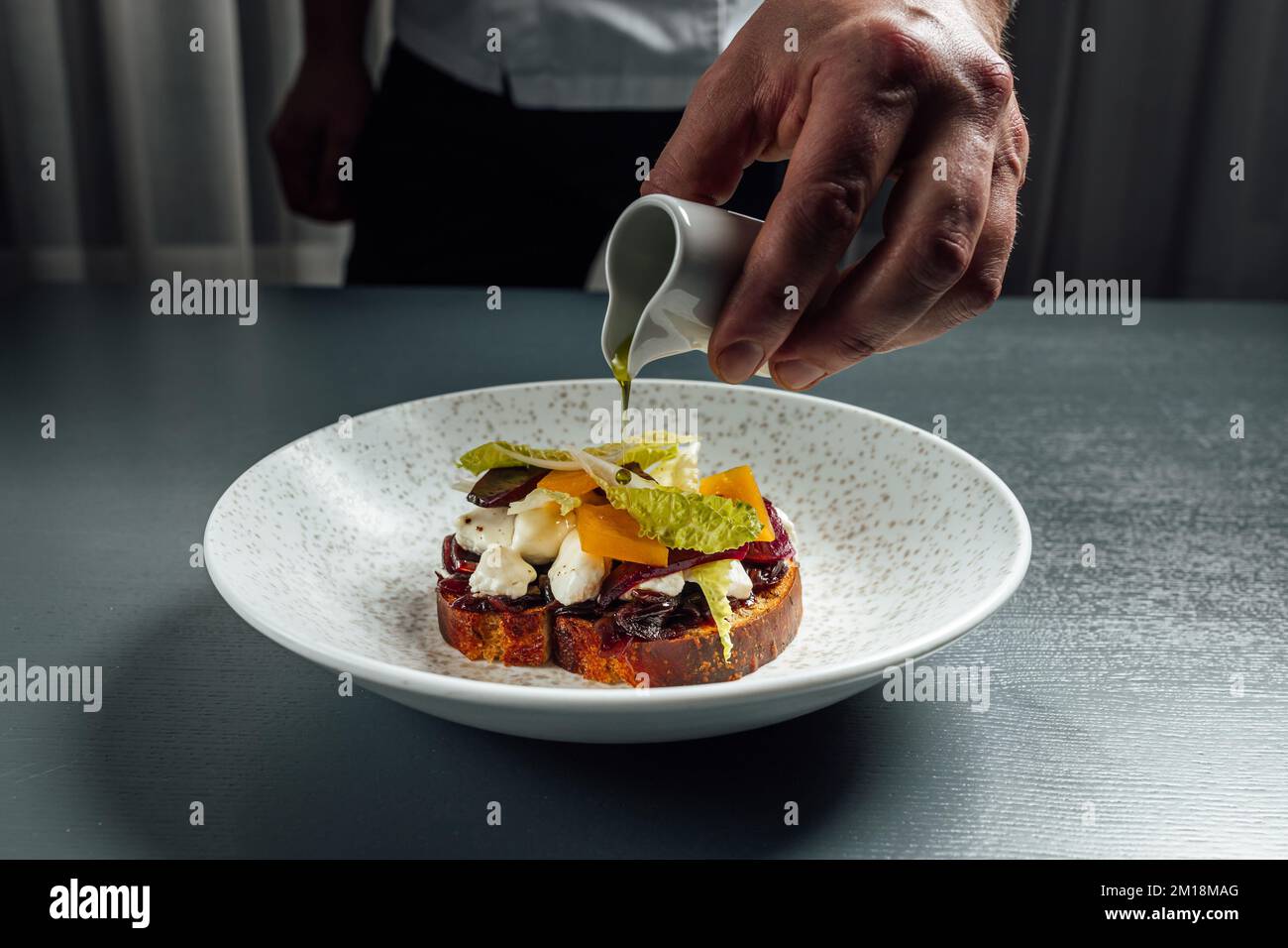 The chef pouring olive oil over Bruschetta with tomato and mozzarella ...