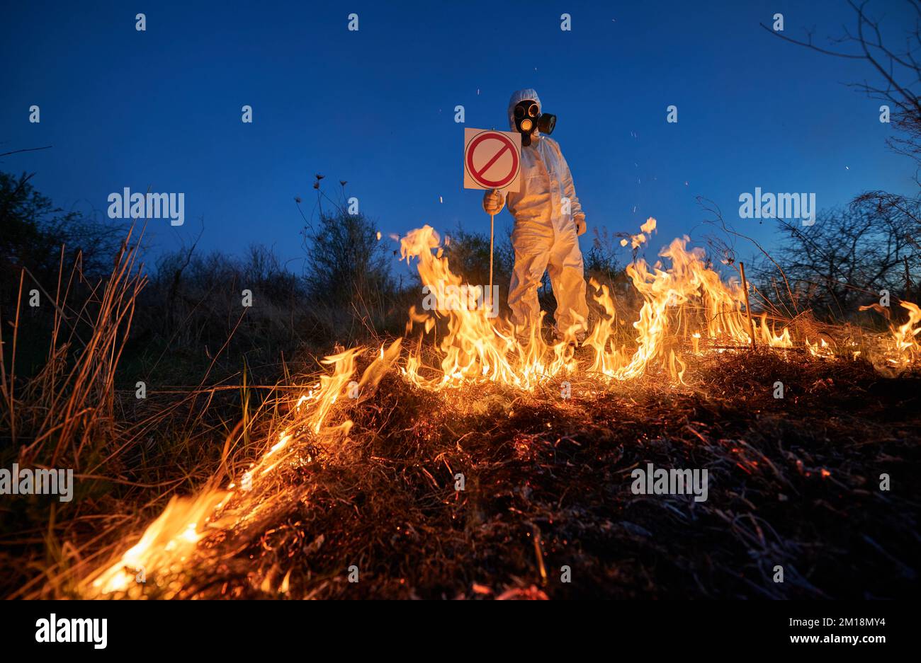 Firefighter ecologist working in field with wildfire at night. Man in ...