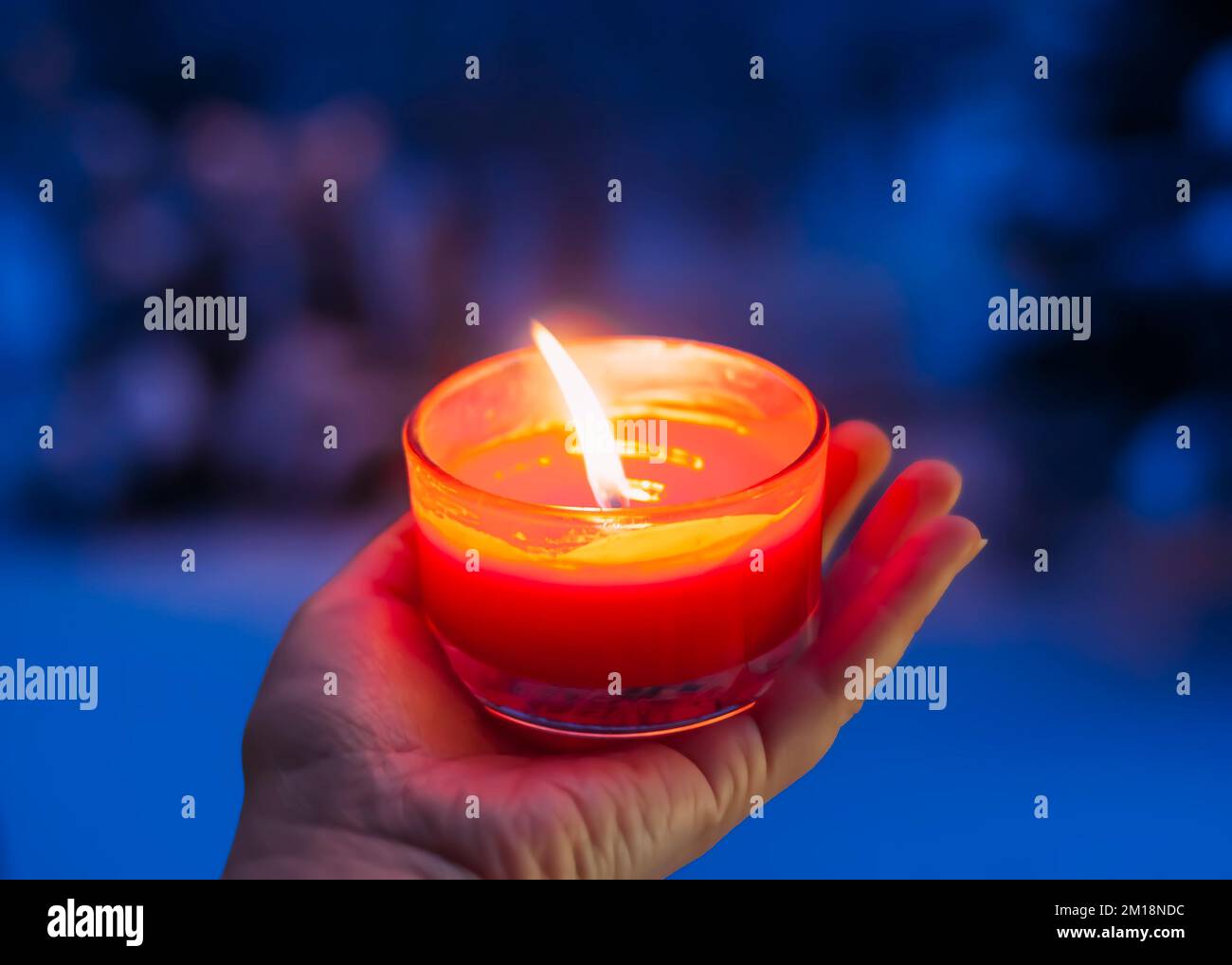 Burning red candle in a hand on winter background Stock Photo - Alamy