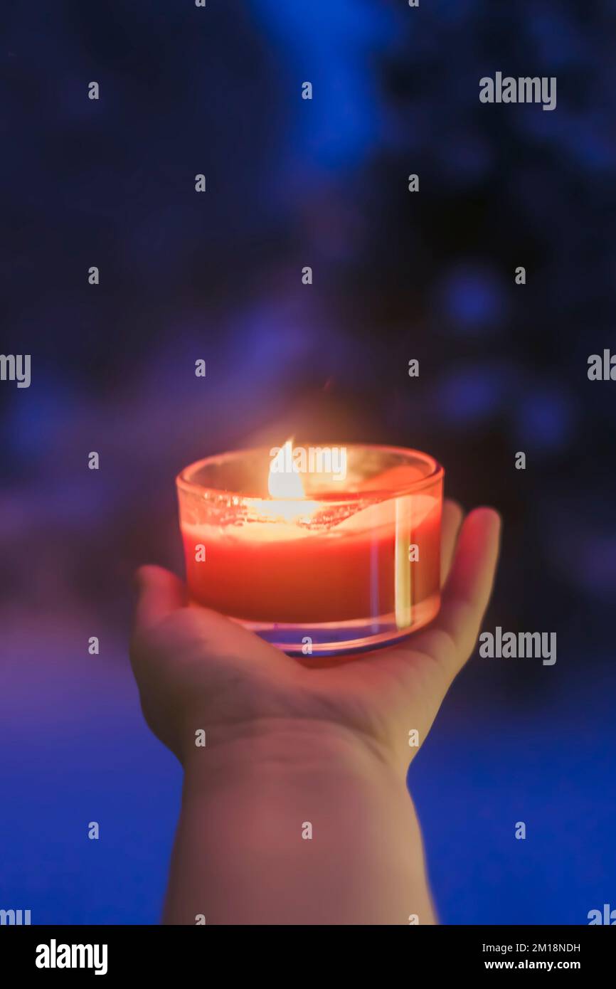 Burning red candle in a hand on winter background Stock Photo - Alamy