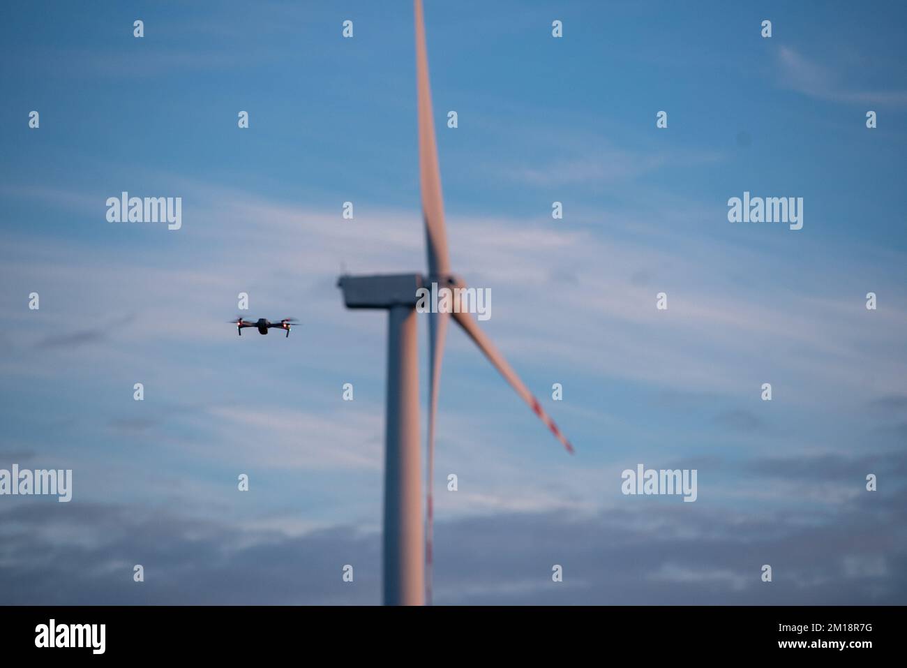 View of flying drone with windmill in the background Stock Photo - Alamy