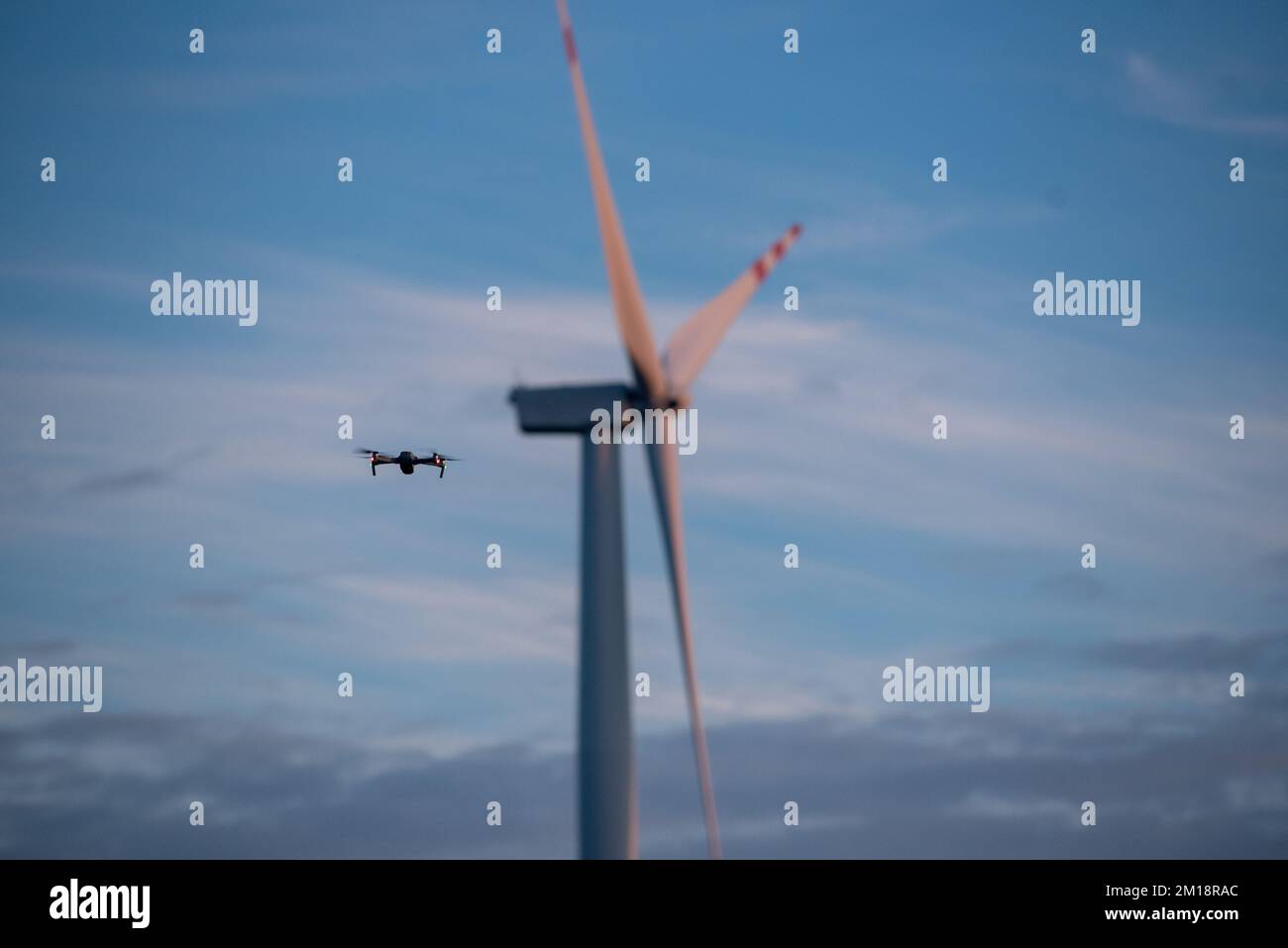 View of flying drone with windmill in the background Stock Photo - Alamy