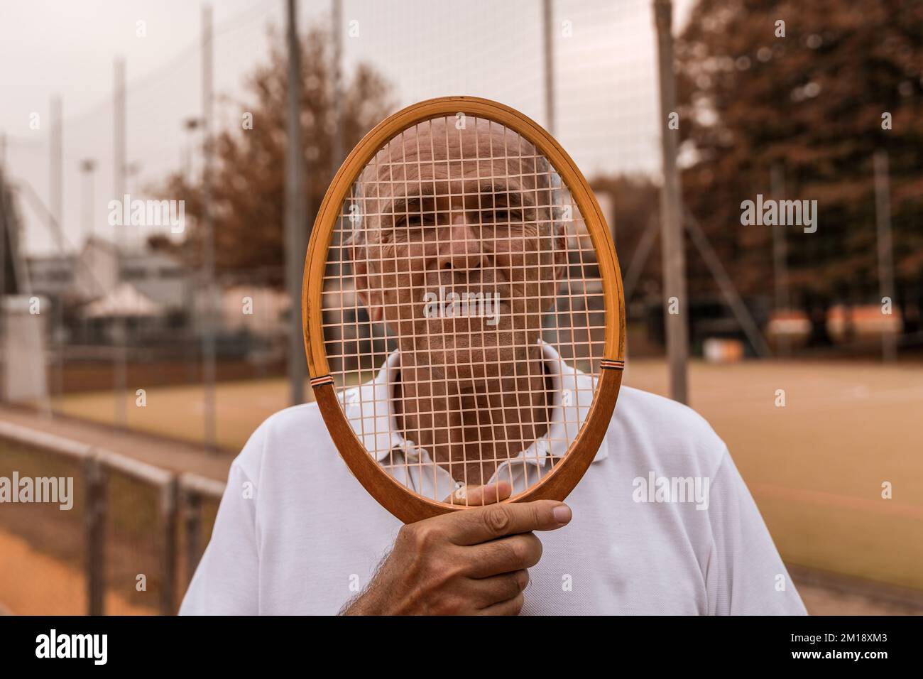 portrait of senior tennis player dressed in sportswear posing with ...