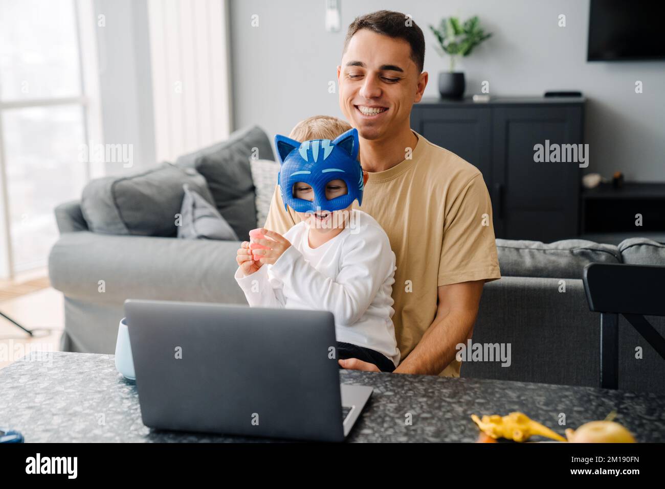 Young white man and little son laughing and using laptop while sitting ...