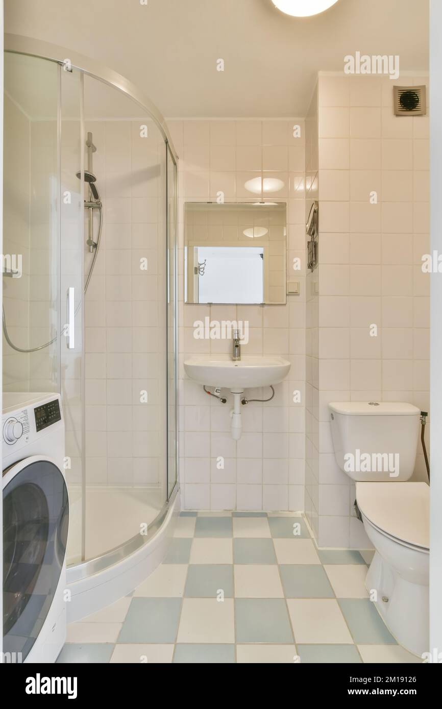 a white and blue tiled bathroom with a washer, toilet, and washing ...