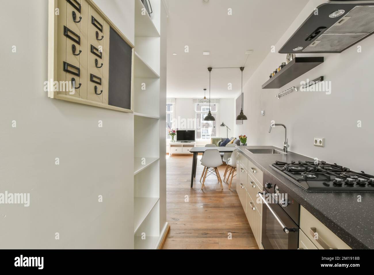 a long narrow kitchen with white walls and wood flooring, along with ...