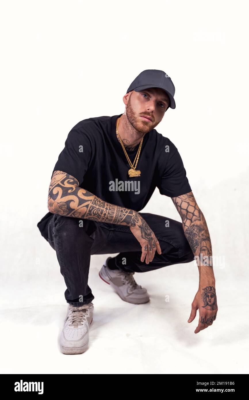tattooed rap singer posing in studio wearing black clothes on a white ...