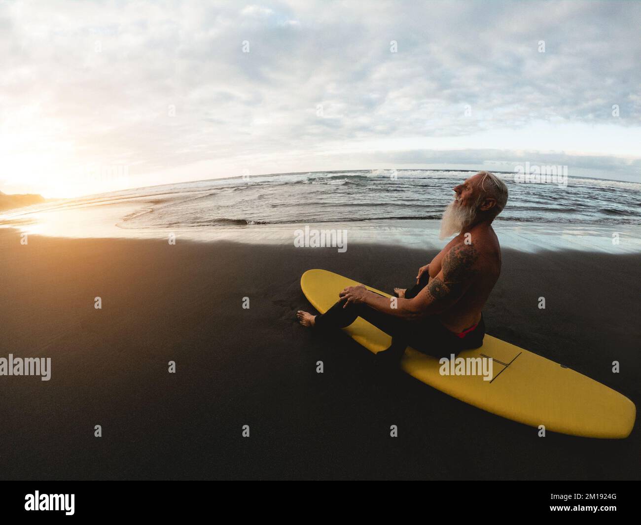 Senior surfer having fun on the beach after surf board training session ...