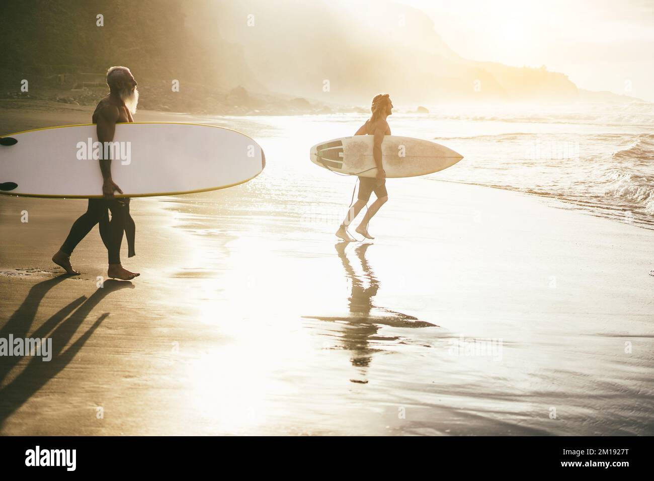 Surfer father and son having fun while surfing on beach - Focus on guy ...