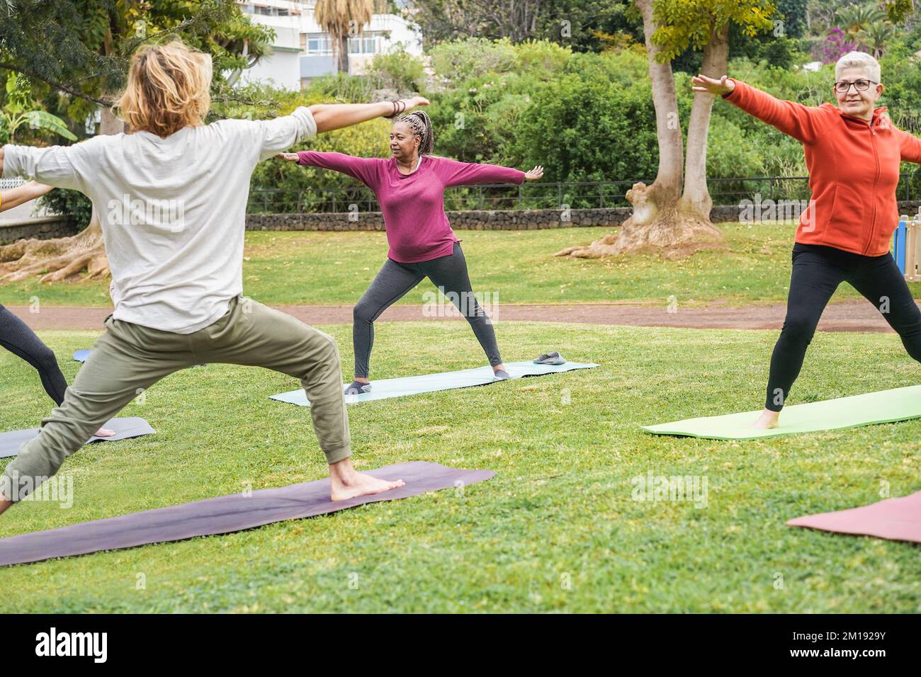 Senior people doing yoga class at city park - Focus on african woman ...