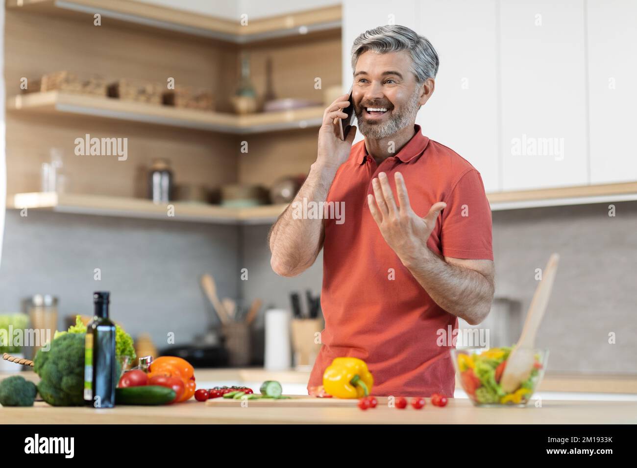 Emotional middle aged man talking on phone while cooking Stock Photo ...