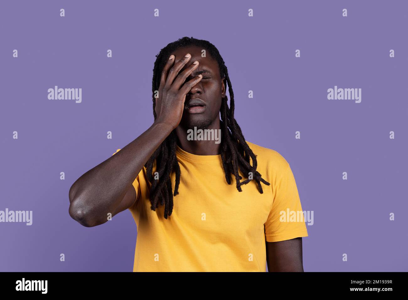 Tired upset black guy touching face over purple studio background Stock ...