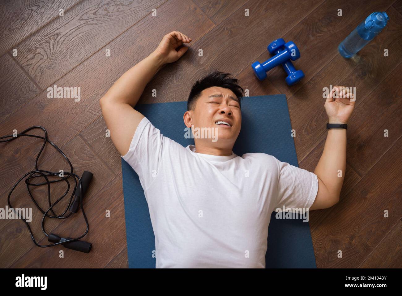Exhausted mature korean man lying on yoga mat on floor with sports ...