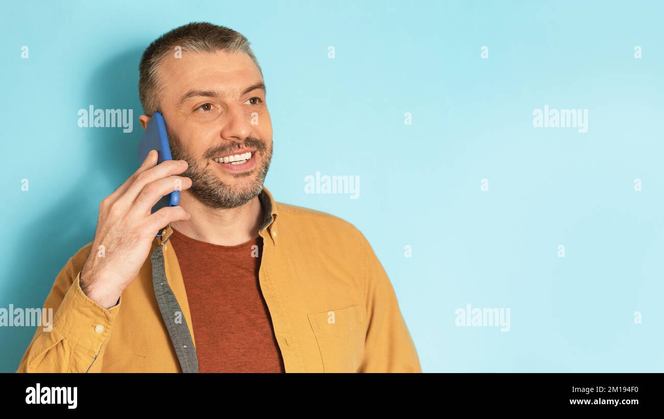 Portrait of mature man talking on his smartphone, looking at copy space ...