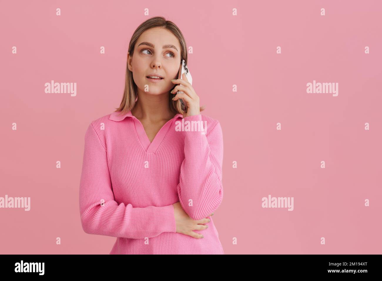 Young cute girl talking on the phone in pink sweater standing over ...