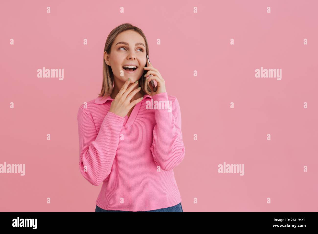 Young cute girl talking on the phone in pink sweater standing over ...
