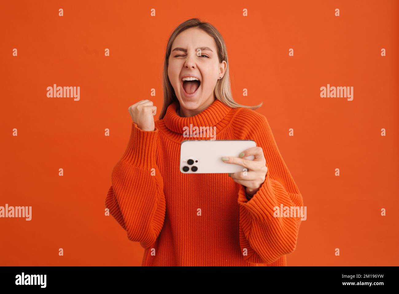Young beautiful enthusiastic girl celebrating victory in mobile game on ...