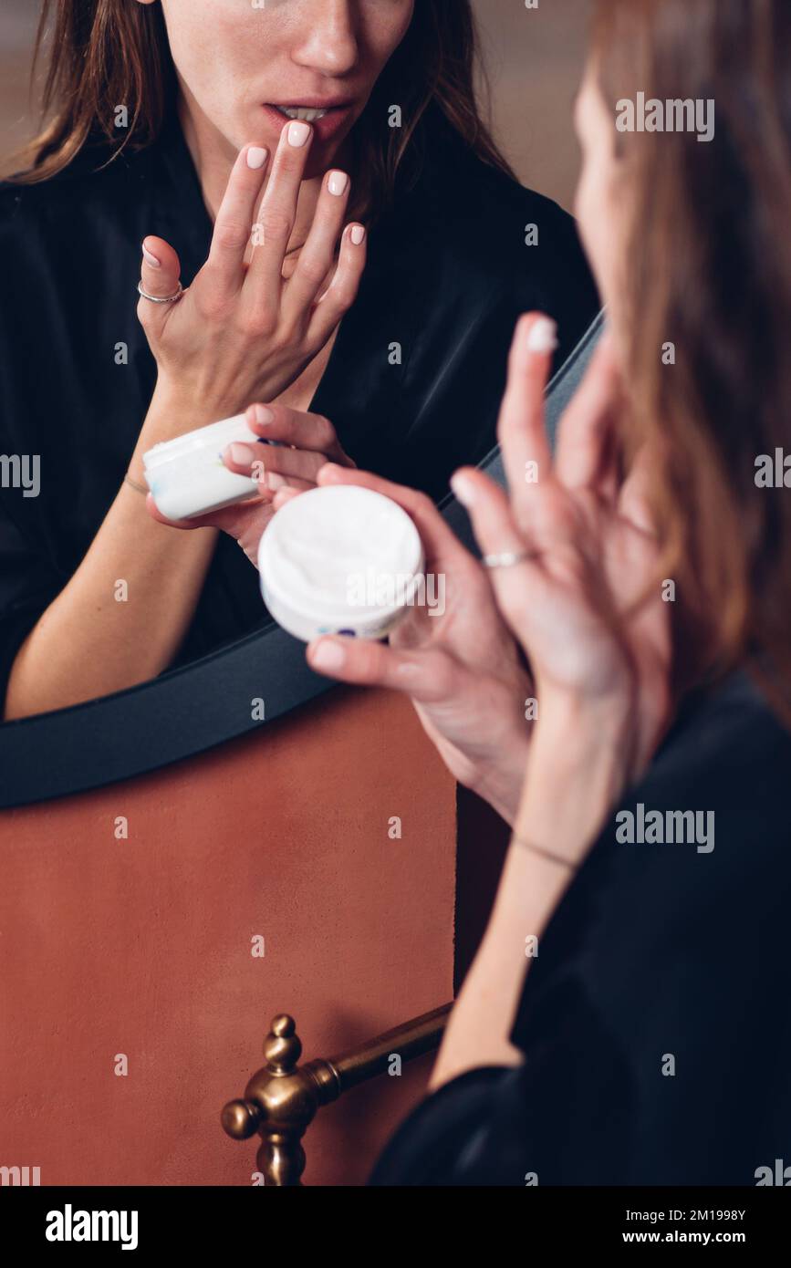 Woman applies nourishing balm to her lips, moisturizing her skin Stock ...