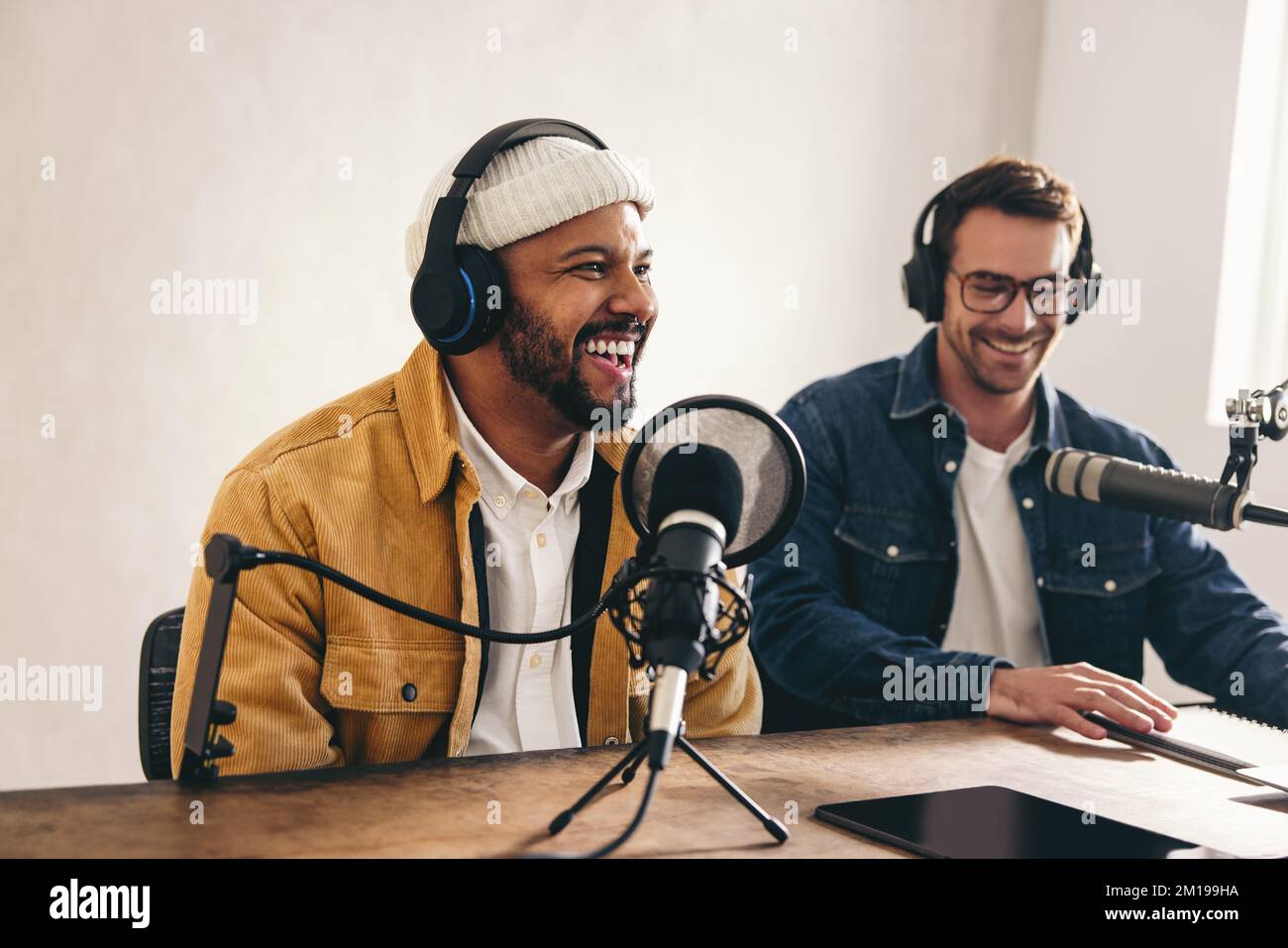 Happy radio presenter smiling while speaking into a microphone in a ...