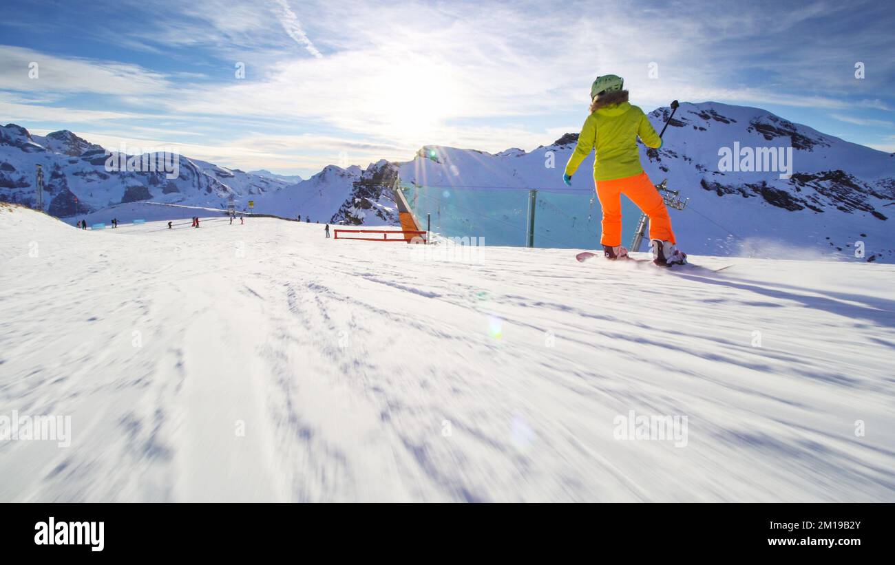 Girl snowboarding on slopes in the Swiss alps. Sun rays and flare ...