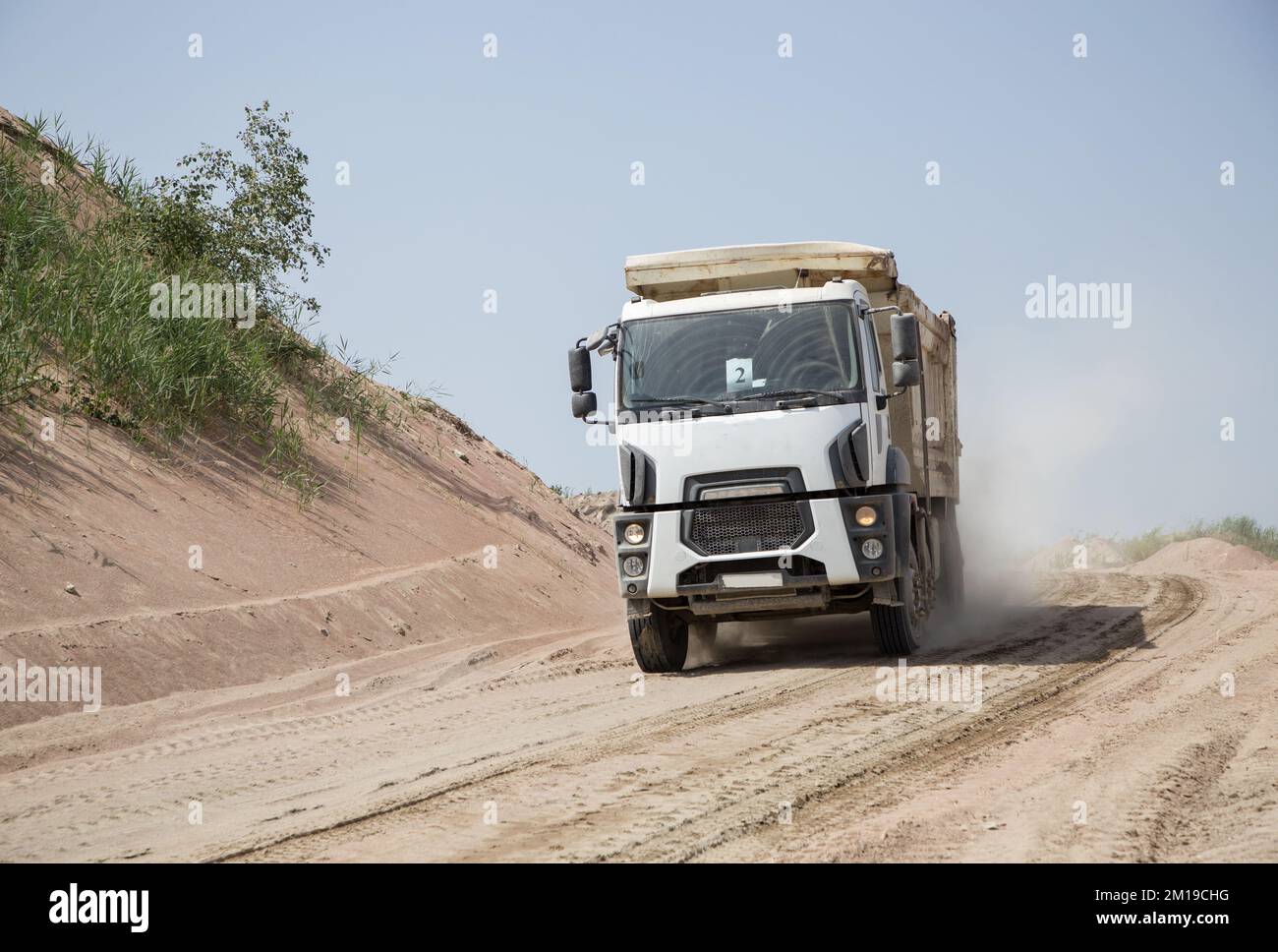 gray dump truck ride on a dirt road in the process of transportation ...