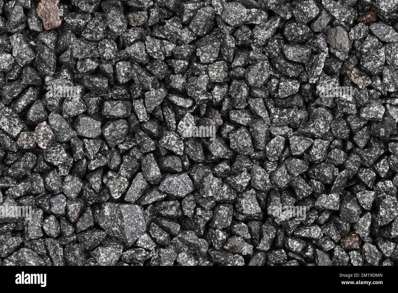 Wet dark gray gravel covering the ground at road construction site, top ...