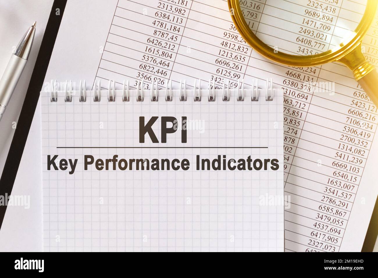 On the table are financial reports, a pen, a magnifying glass and a ...