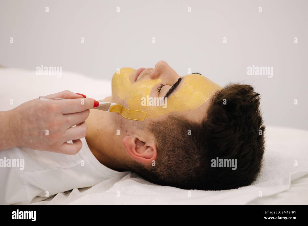 Handsome man having golden mask in beauty studio. Male in spa salon ...