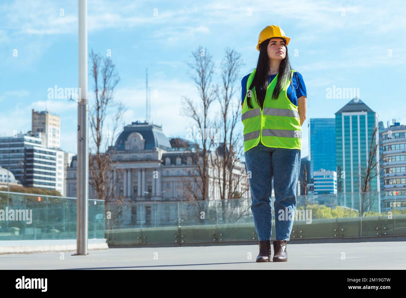 young caucasian woman engineer with safety helmet and vest, standing on ...