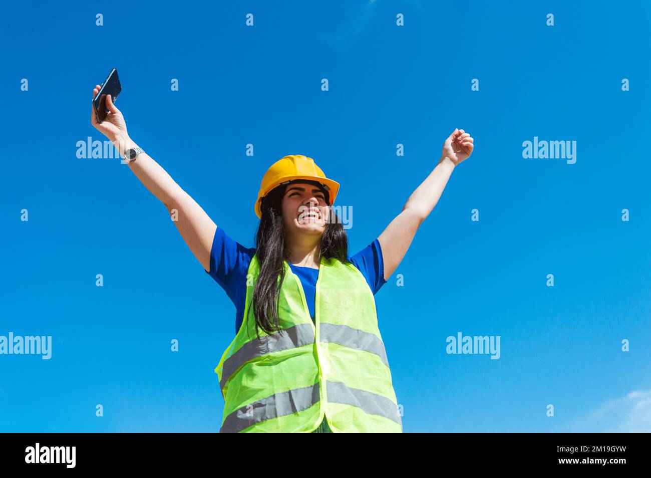 young caucasian engineer woman, she is wearing a yellow helmet and ...