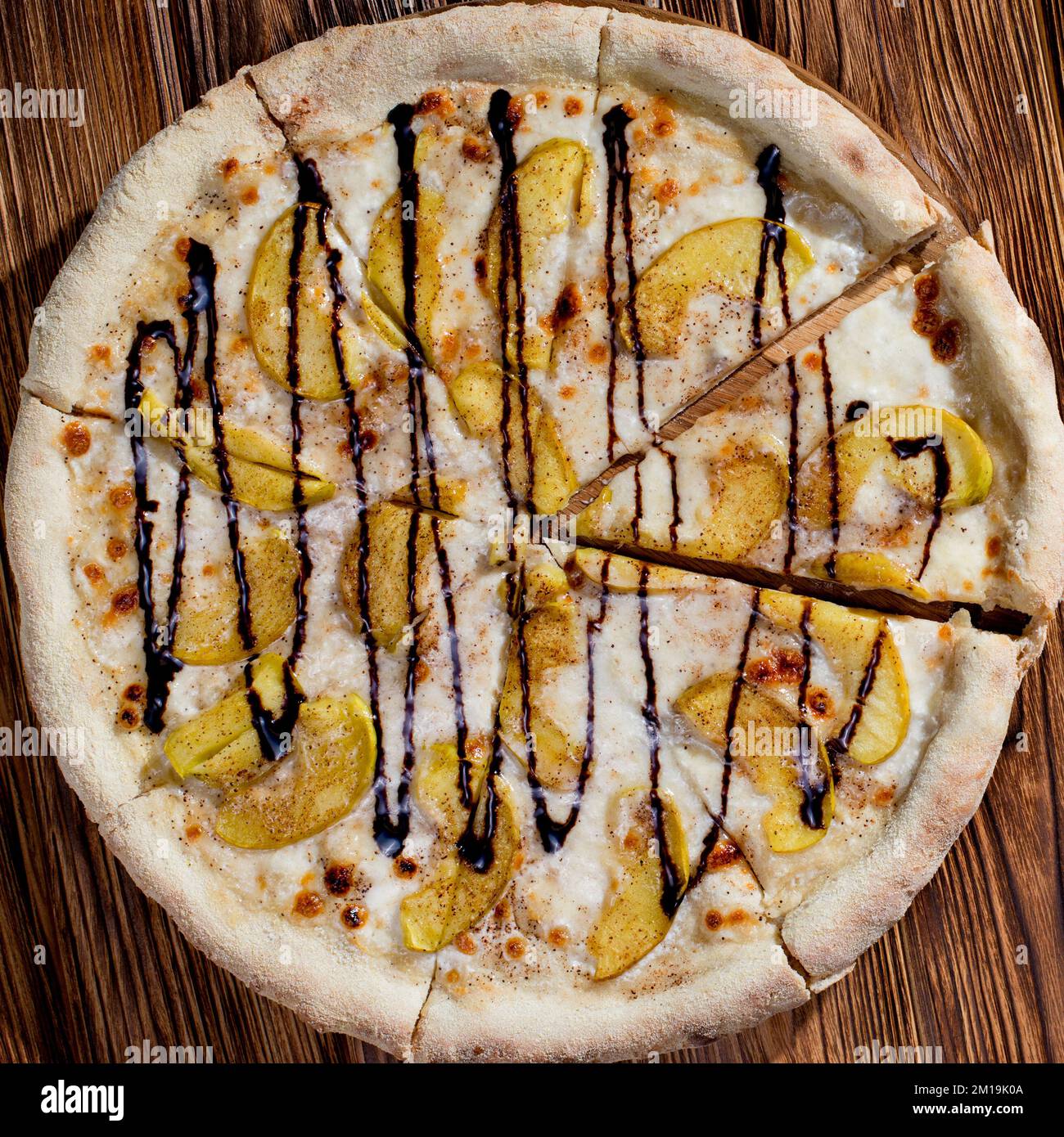 Sweet delicious pizza with apple, cinnamon, chocolate on wood ...