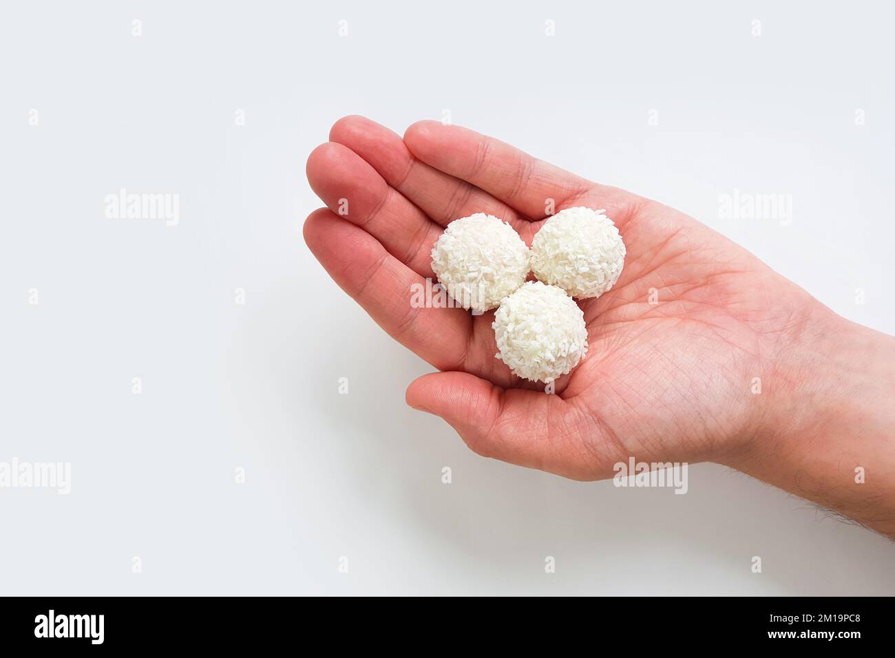 Three round candies of white chocolate truffles covered in shredded ...