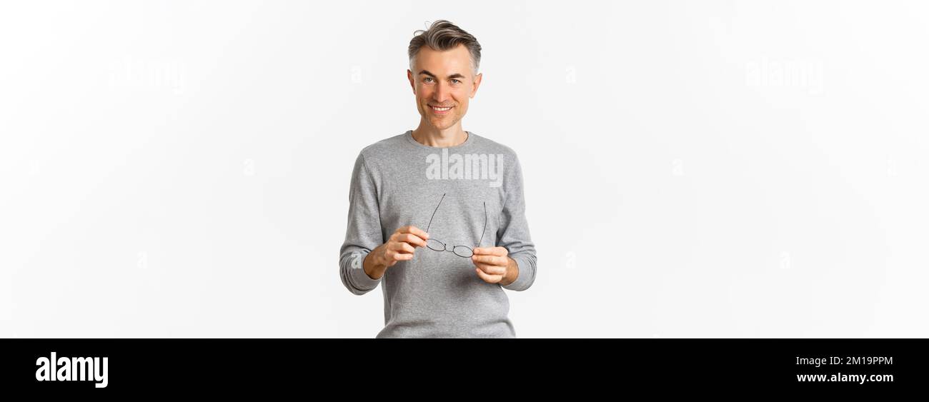 Portrait of handsome and confident man in grey sweater, taking-off ...