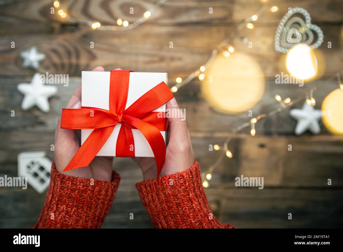 Gift box in female hands on a blurred background with bokeh, top view Stock Photo - Alamy
