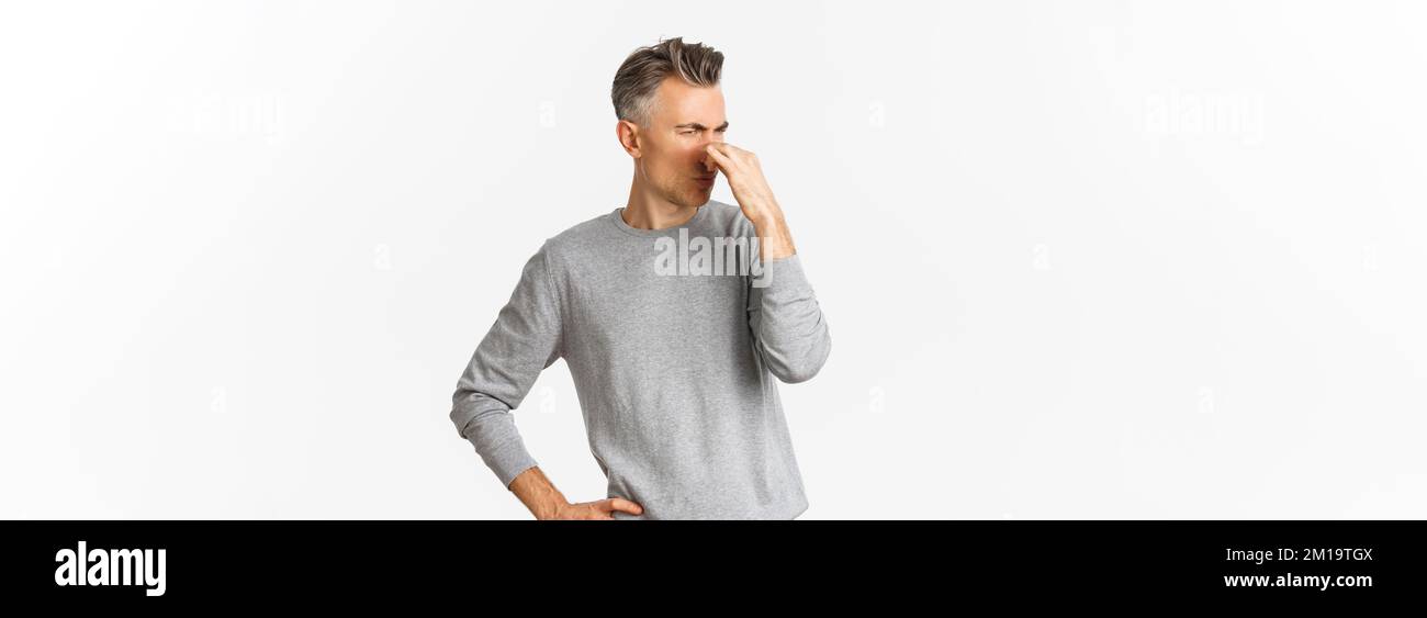 Portrait of handsome middle-aged man shut nose from disgusting smell ...