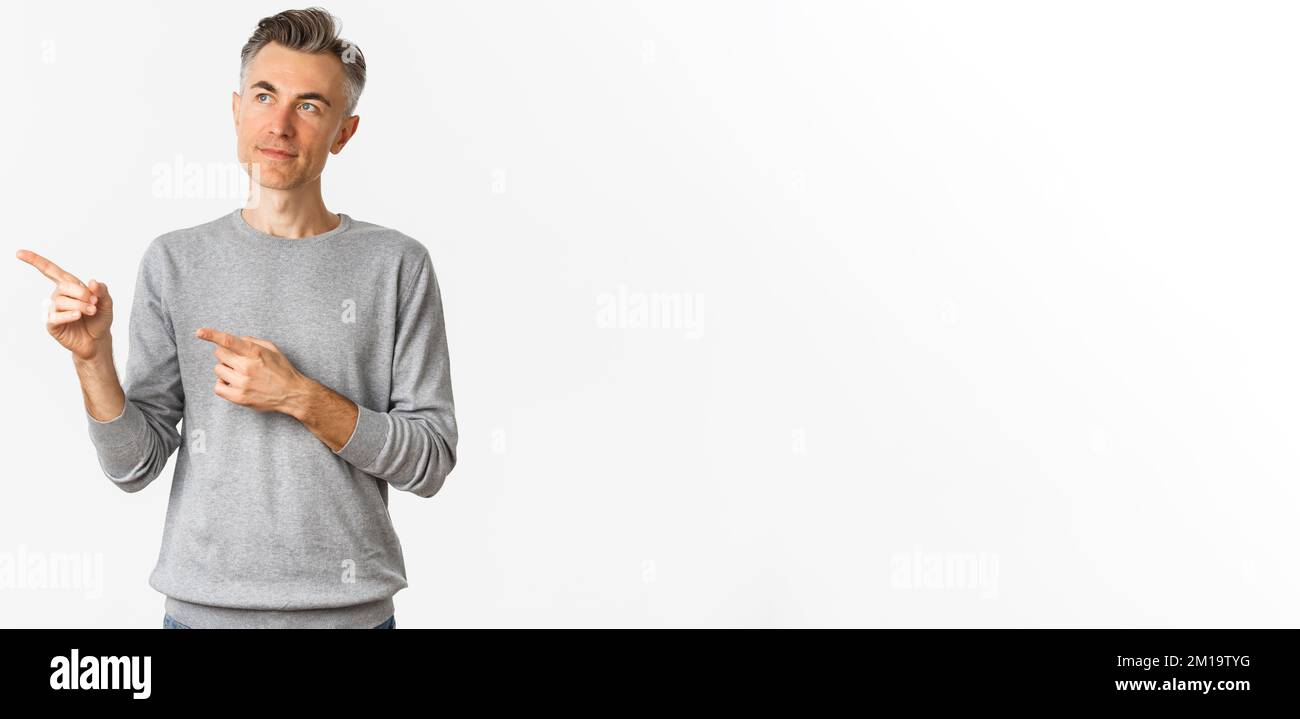 Image of thoughtful middle-aged man making choice, looking and pointing ...