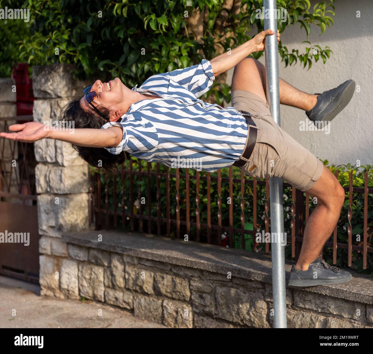 A young happy male posing as a dancer on a pole outdoors Stock Photo ...