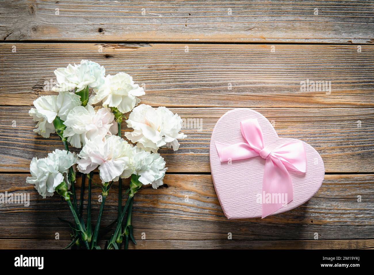 Bouquet of flowers and heart shaped gift box on wooden background, flat ...