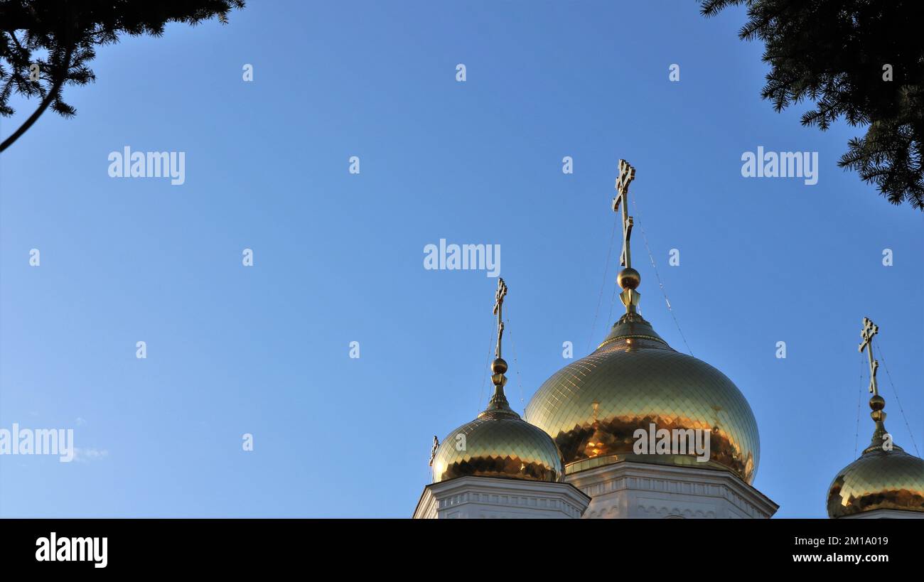 three gilded domes with Orthodox crosses against a clear blue sky ...