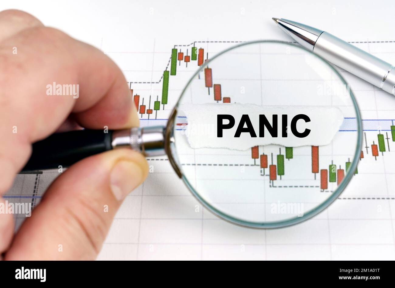 Economy concept. A man looks through a magnifying glass at charts and ...
