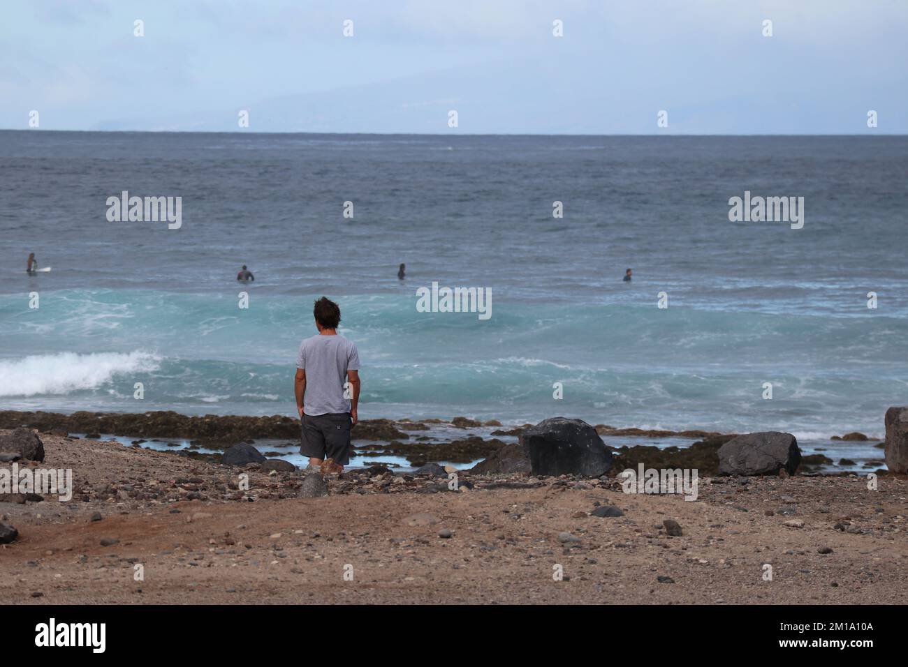 A man looking at the sea where surfers ride the waves Stock Photo - Alamy