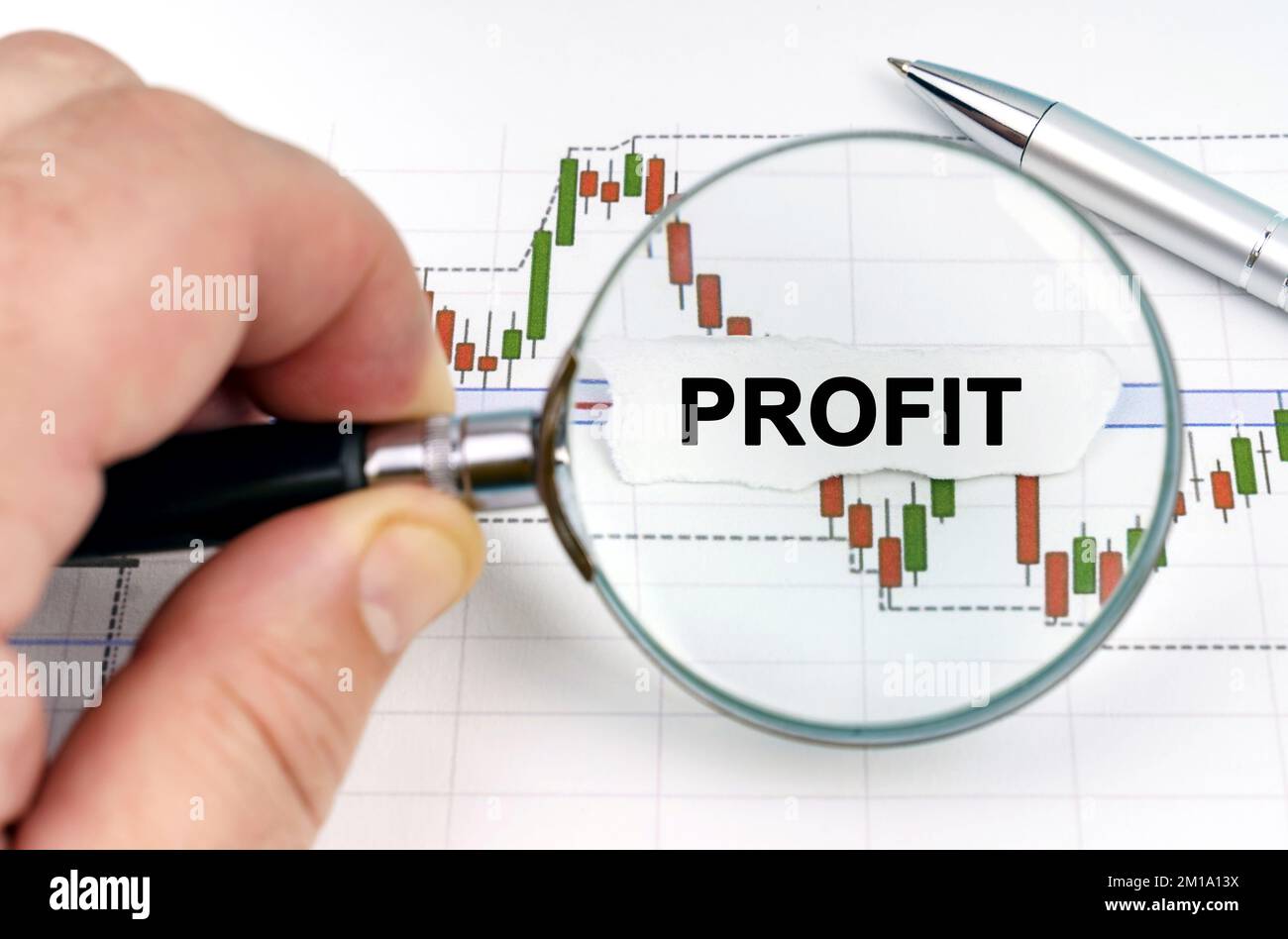 Economy concept. A man looks through a magnifying glass at charts and ...