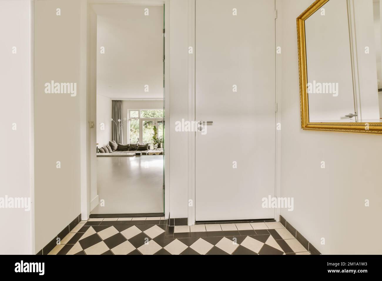 a hallway with black and white checkered flooring, mirror on the wall and an ornate gold framed ...