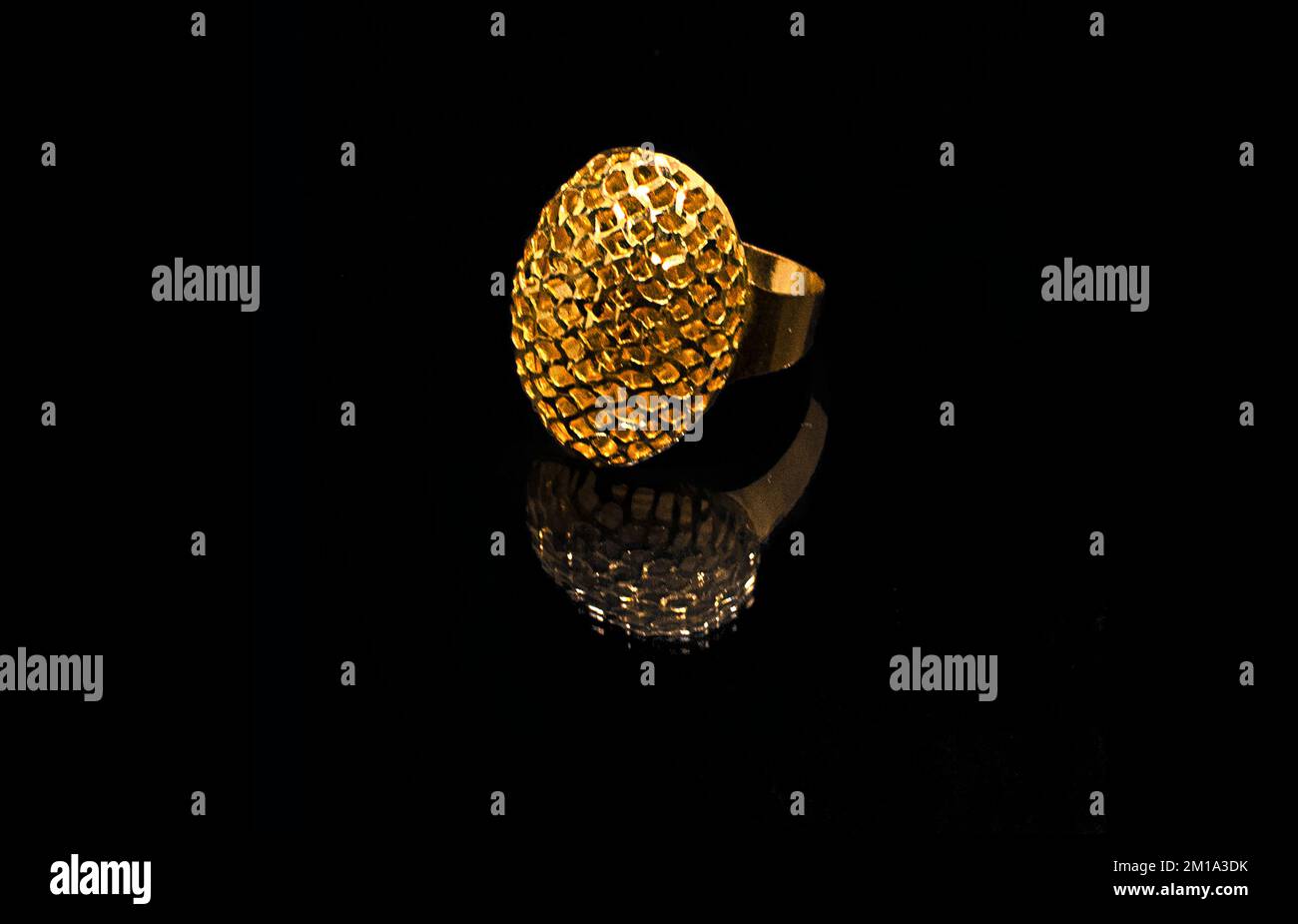 A closeup of a gold ring on a black background with the reflection ...