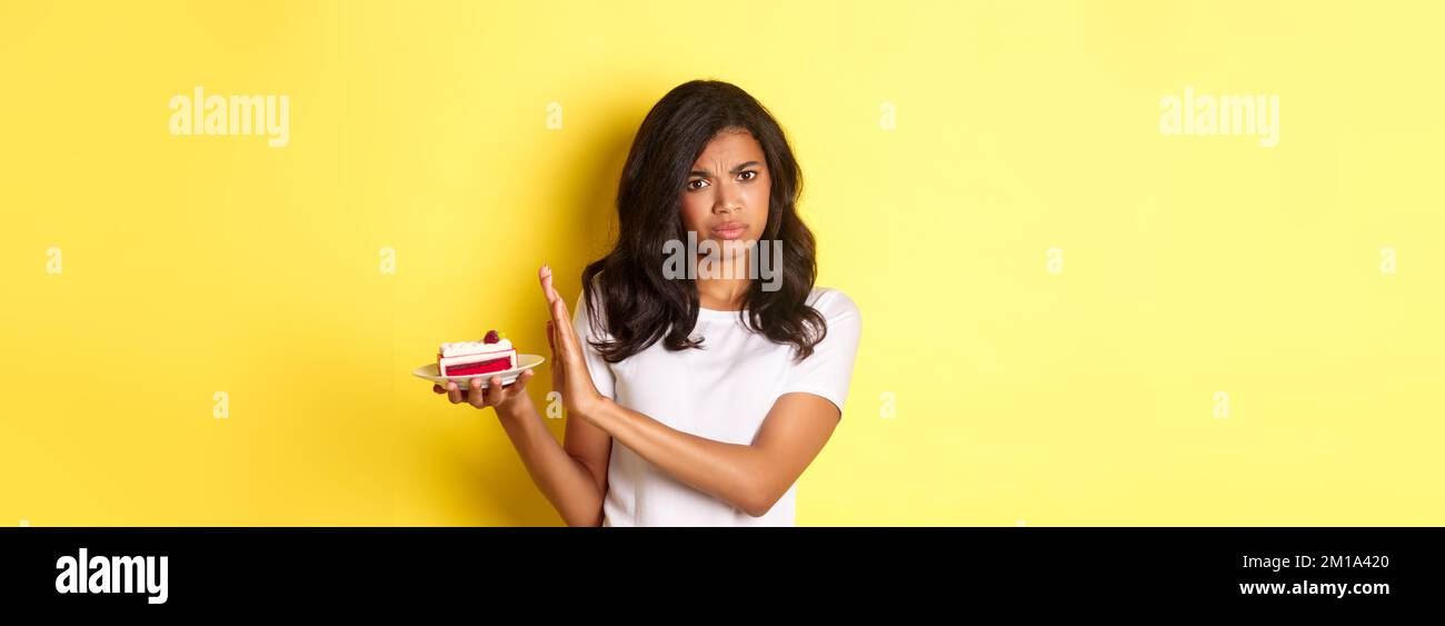 Image of displeased african-american girl decline to eat a cake ...