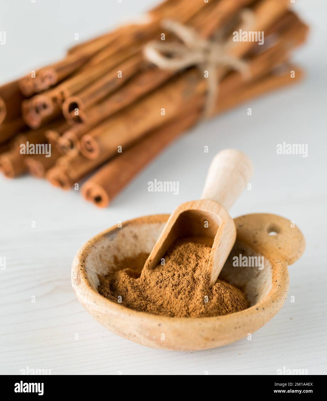 A small clay pottery bowl of cinnamon powder with cinnamon sticks in ...