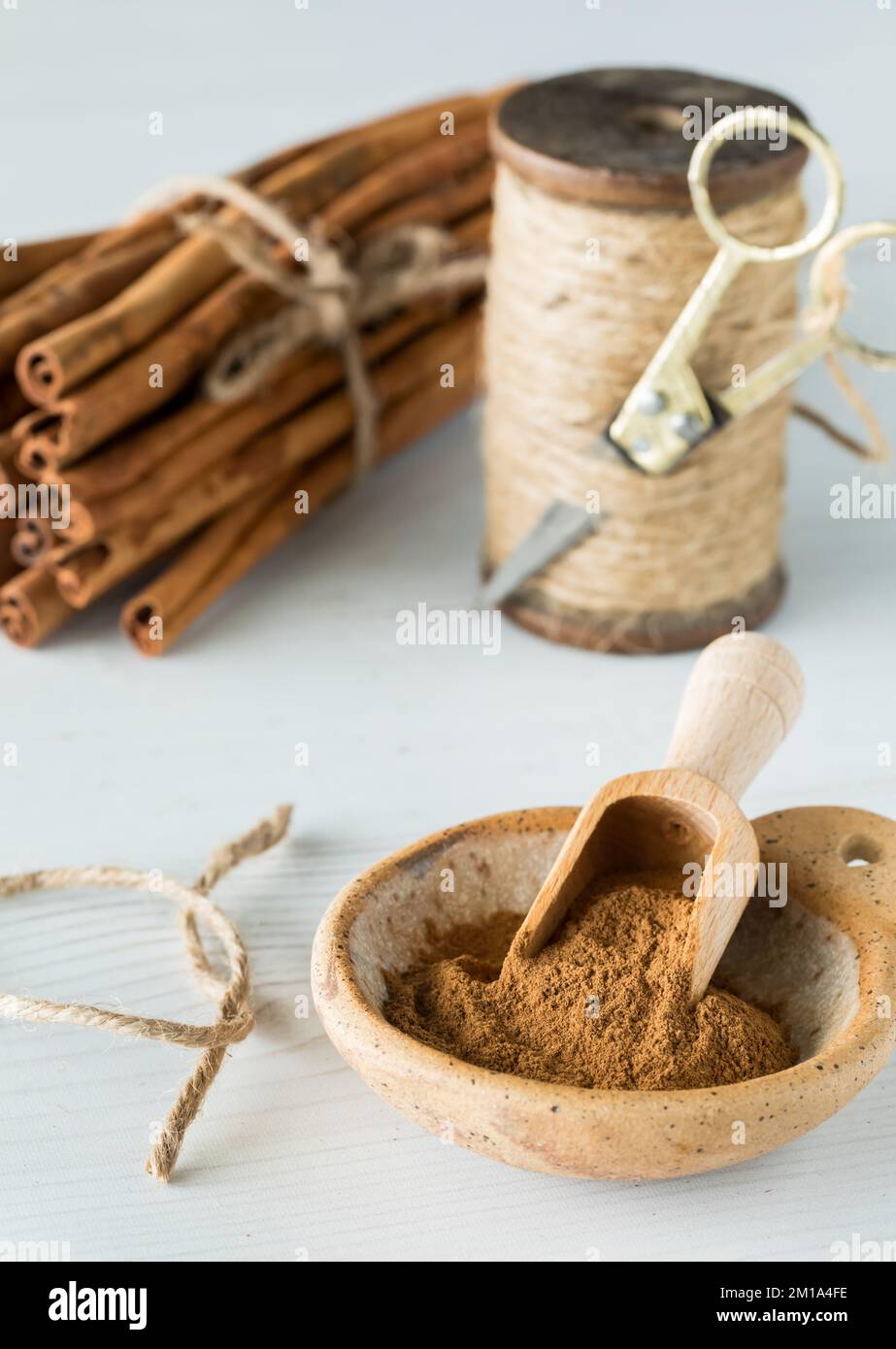 Cinnamon powder with a bundle of cinnamon sticks and a spool of twine ...
