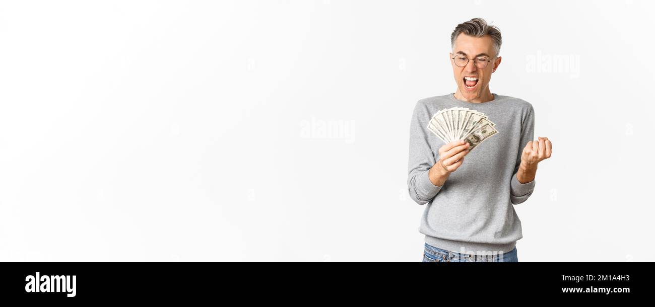 Image of cheerful middle-aged man in glasses and gray sweater, winning ...