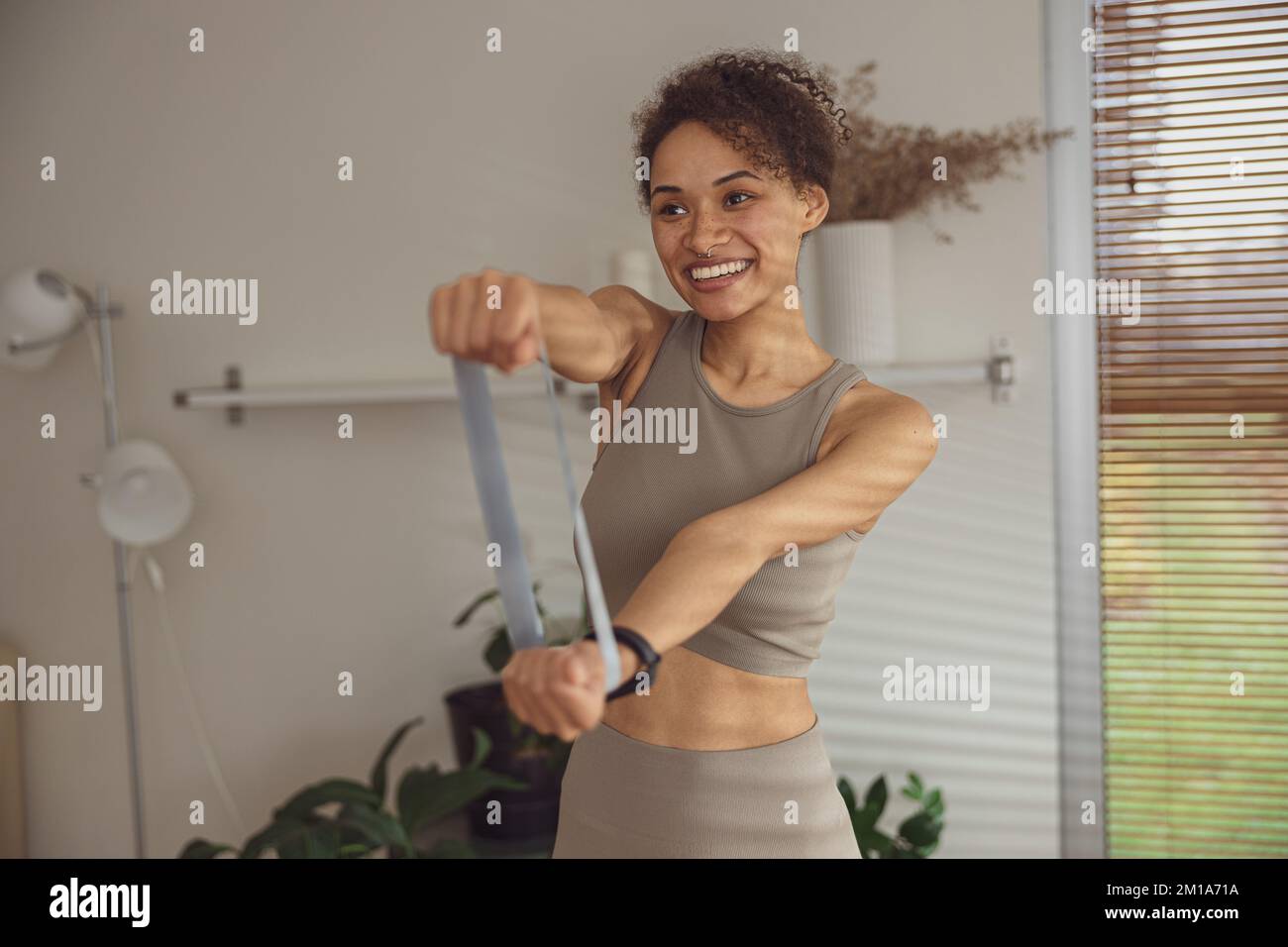 Slim woman doing exercises for hands with elastic band by online ...